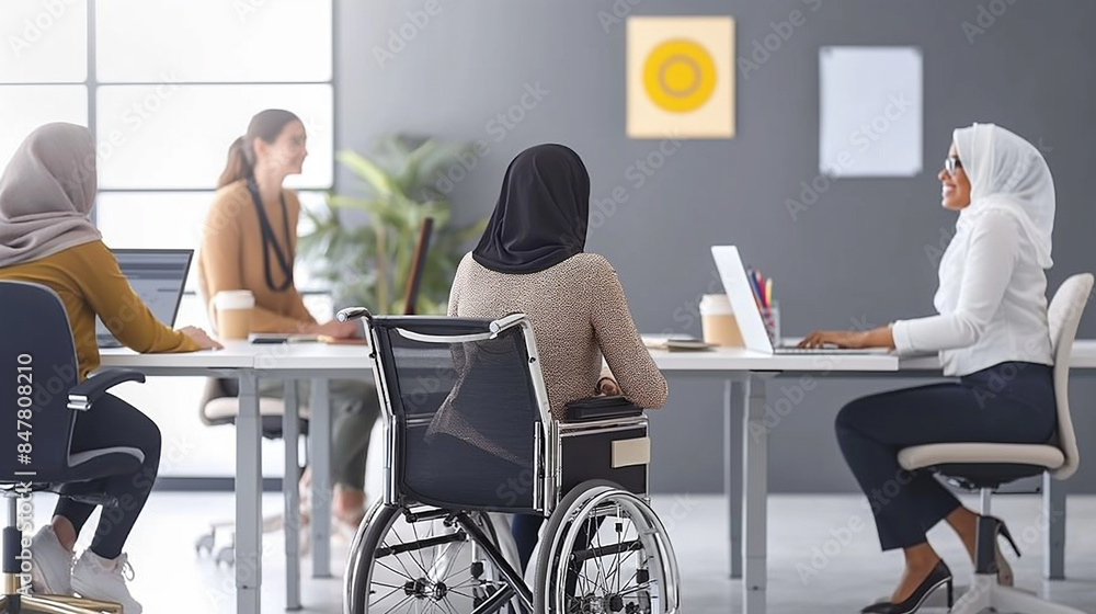 An inclusive office setting shows a happy Muslim woman engaging with ...