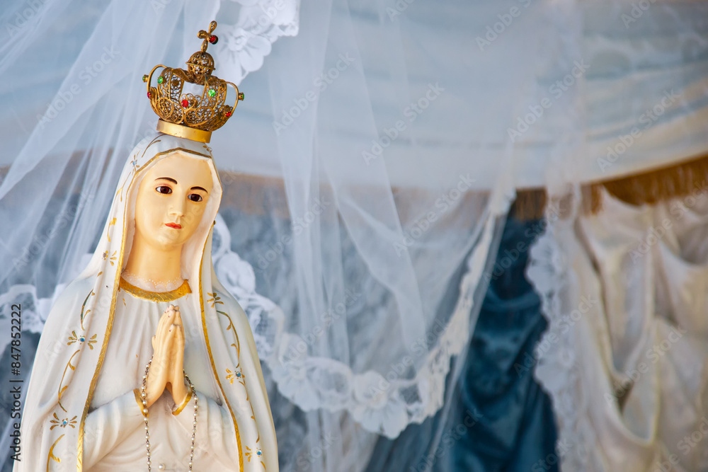 Statue of our lady of fatima with joined hands wearing a crown and a ...