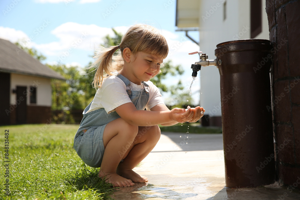 Water scarcity. Cute little girl drawing water with hands from tap ...