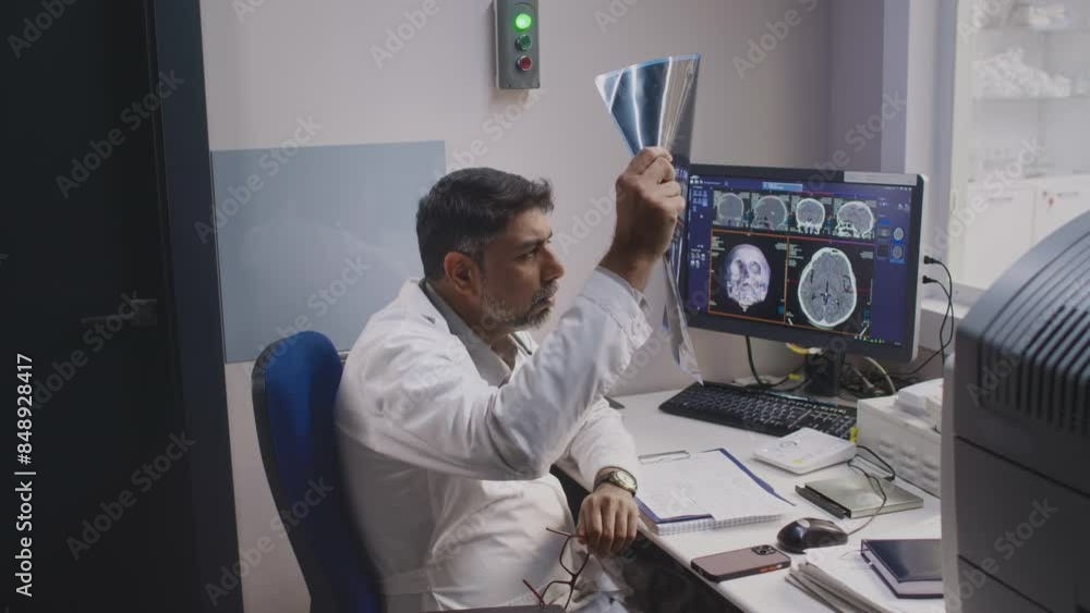Medium shot of mature male radiologist wearing white lab coat and ...