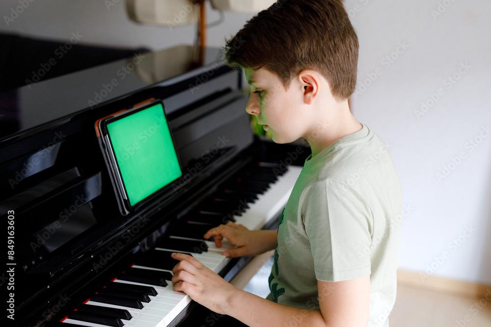 School boy learning play piano with tablet app. Child having fun with ...