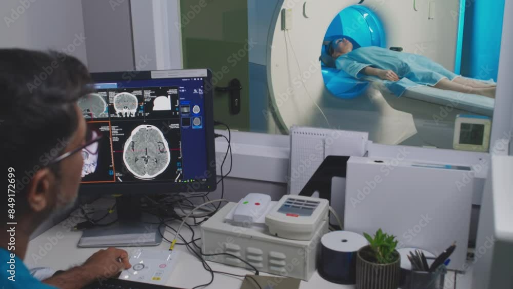 Back view of multiethnic male medical imaging specialist sitting in MRI ...