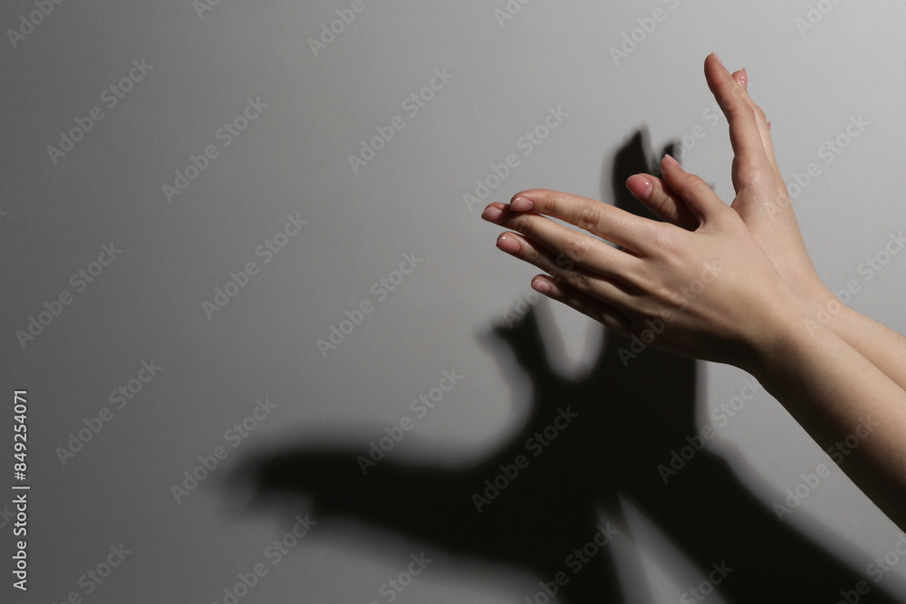 Shadow puppet. Woman making hand gesture like bird on grey background ...