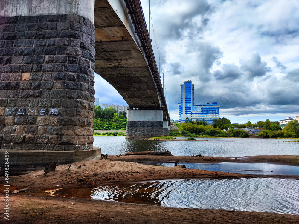 Expansive Bridge Arching Over River With Cloud-Filled Sky on a Bright ...