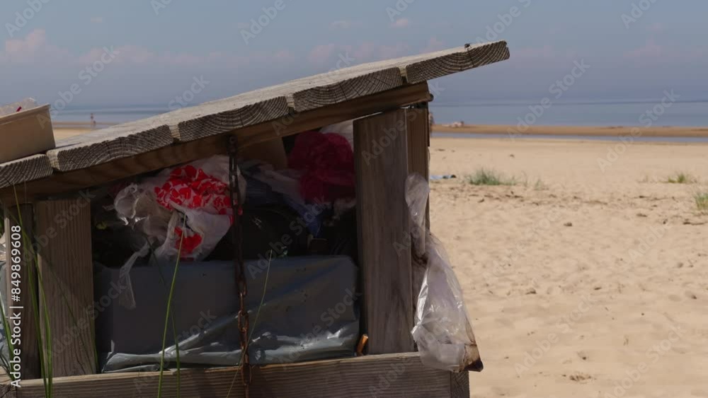 A deserted beach with debris and a wooden shelter under a clear sky ...