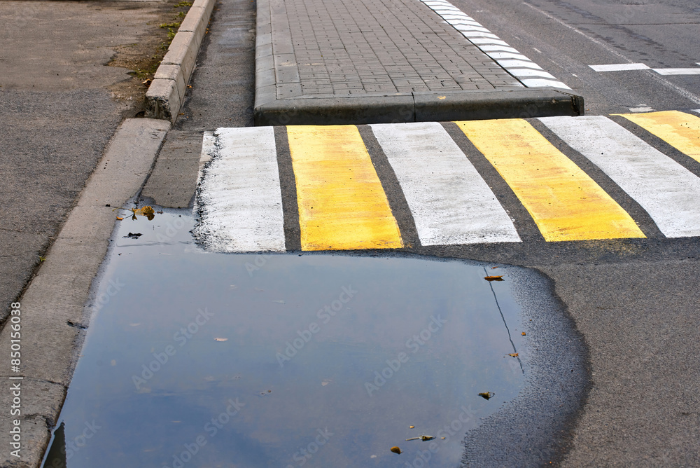 Puddle at zebra crosswalk. City street view of a zebra crossing with ...