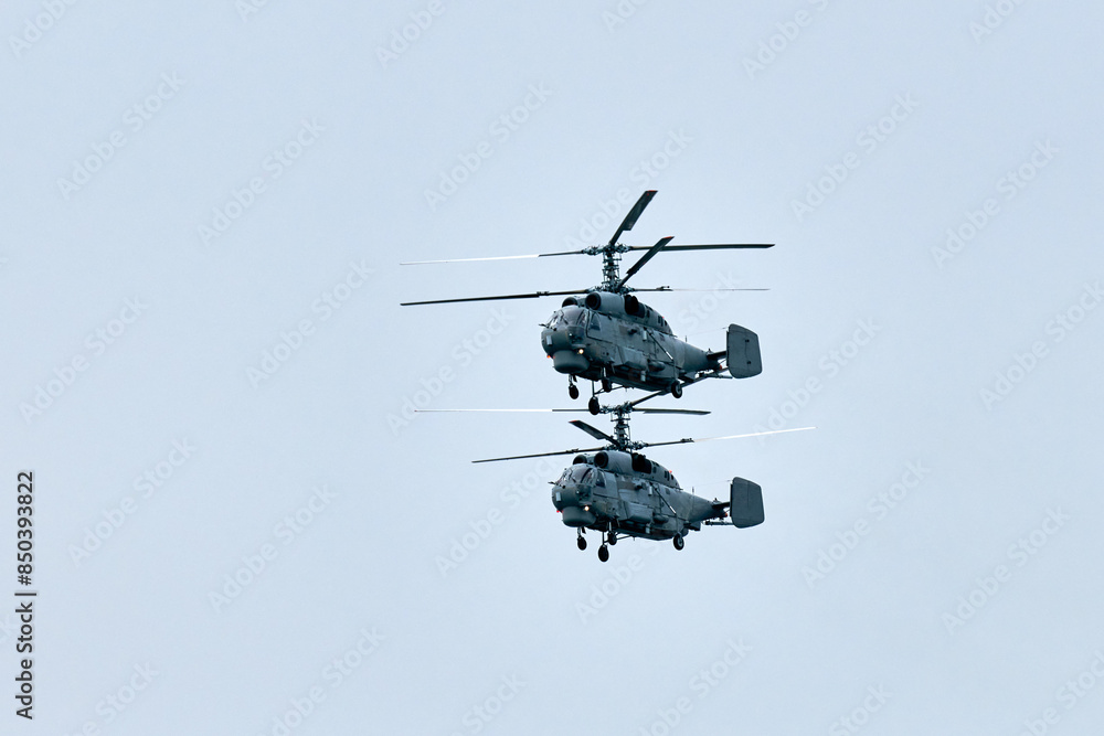 Two Russian military helicopters armed with missiles flies in blue sky ...