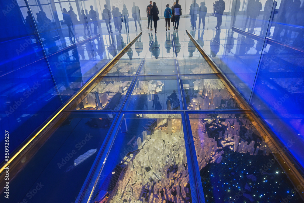 Visitors stand on a glass floor with reflections adding depth to the ...
