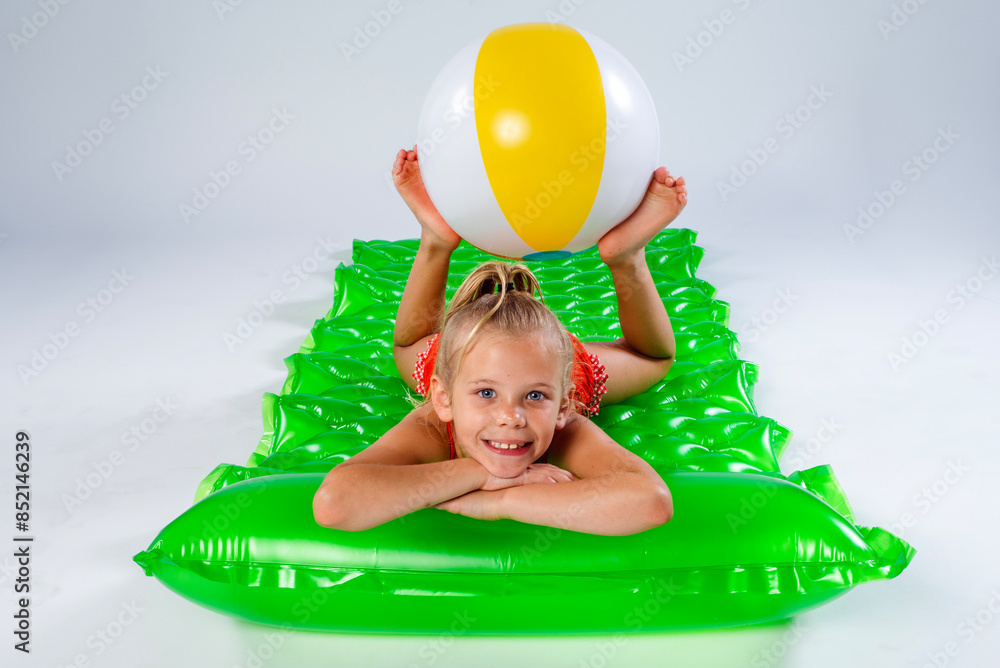 Happy young girl floating on an inflatable pool raft, playfully holding ...