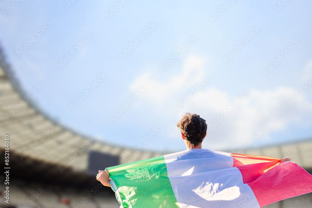 Passionate fan with the Italian flag draped over shoulders, standing ...