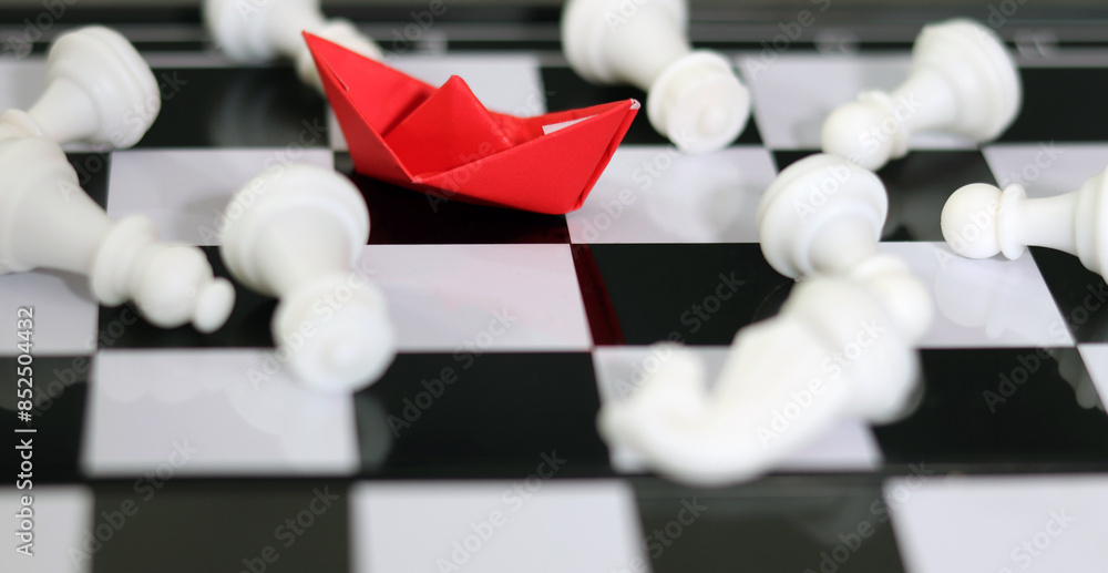 Red paper boats on the chessboard and fallen white chess horses. Chess ...