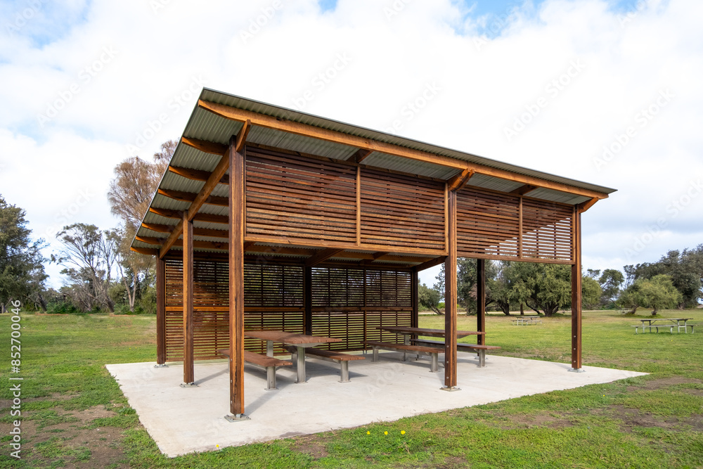 A wooden pavilion or gazebo with a peaked roof, featuring public bench ...