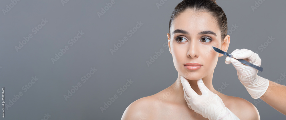 A young woman is receiving a cosmetic surgery procedure performed by a ...