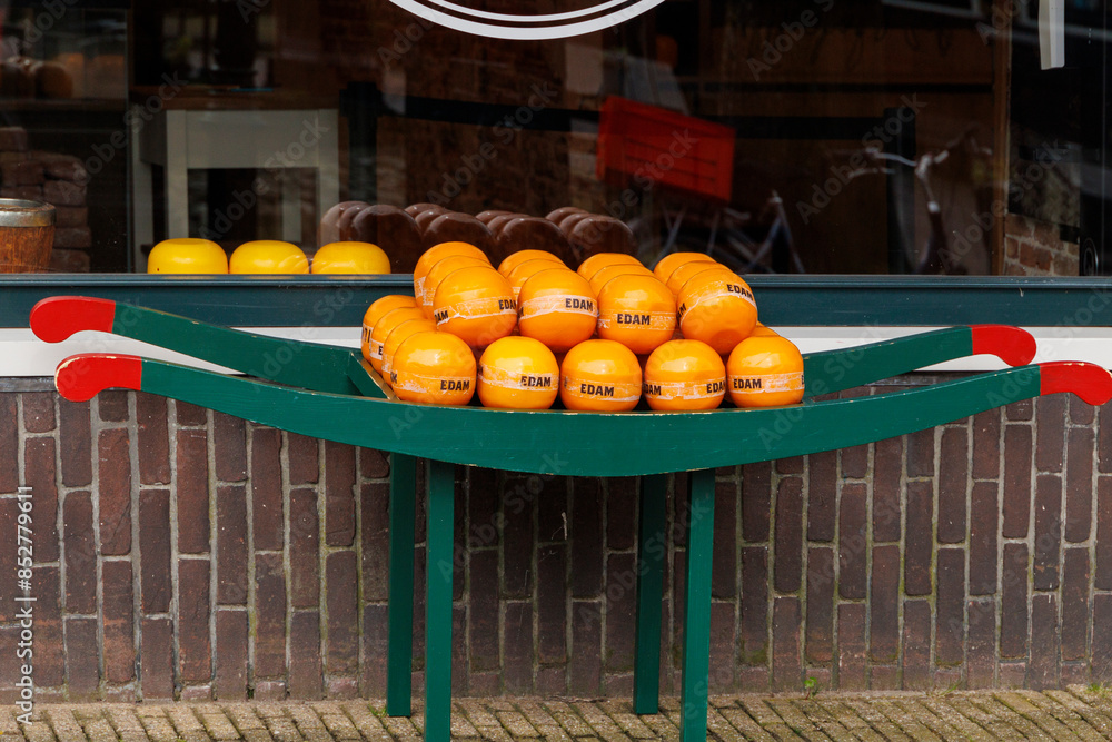 Yellow Edam cheese balls on a green rack in front of a shop window with ...