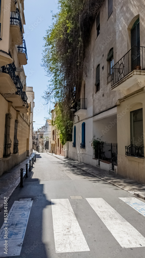 Sunny Mediterranean street with shadows casting over a pedestrian ...