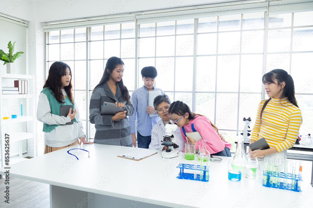 Senior Asian female teacher or scientist teaching group of diverse ...