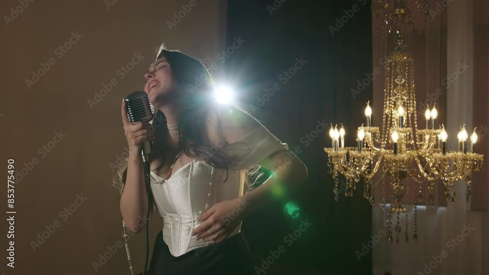 Sensual young girl in vintage outfit sings into retro microphone on ...