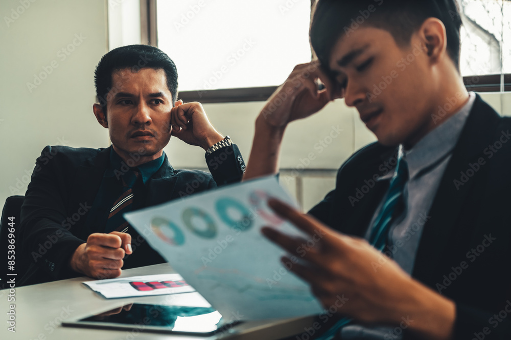 Unhappy business manager and young businessman partner in meeting room ...