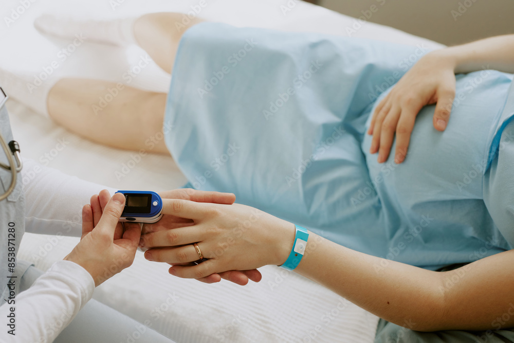 Nurse holding pregnant patients hand and examining her saturation with ...
