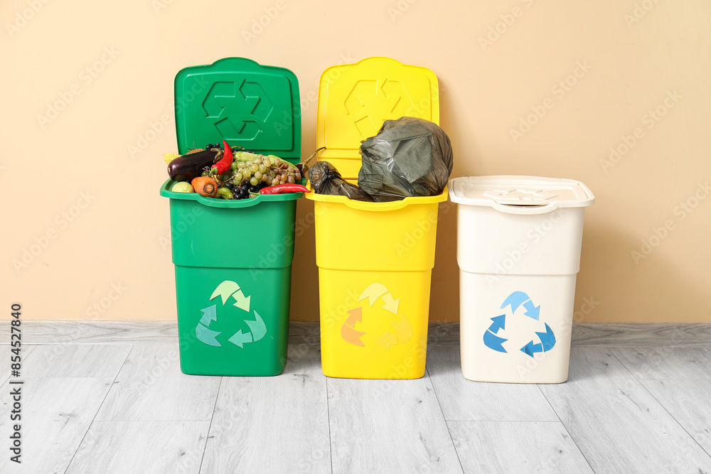 Containers for trash with food waste and full garbage bag near beige ...