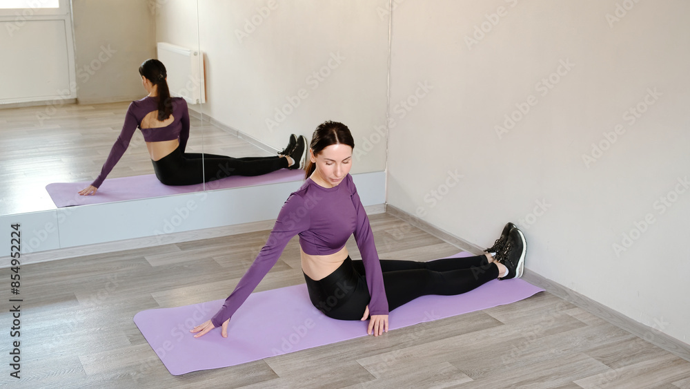 Athletic 30 year woman is doing stretching exercise rotating body to ...