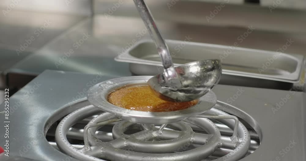 Turkish kunefe or kunafa cooking on a stove. Chef pours syrup on ...