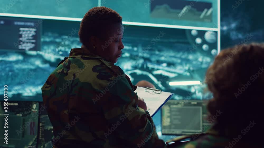 Female brigadier general gather intelligence reports on a big screen ...