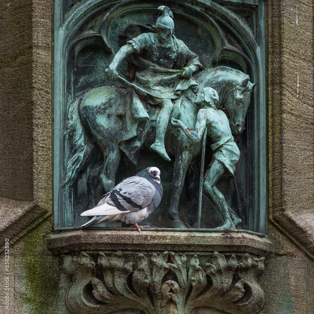 A pigeon perches on a historic stone sculpture depicting a medieval ...