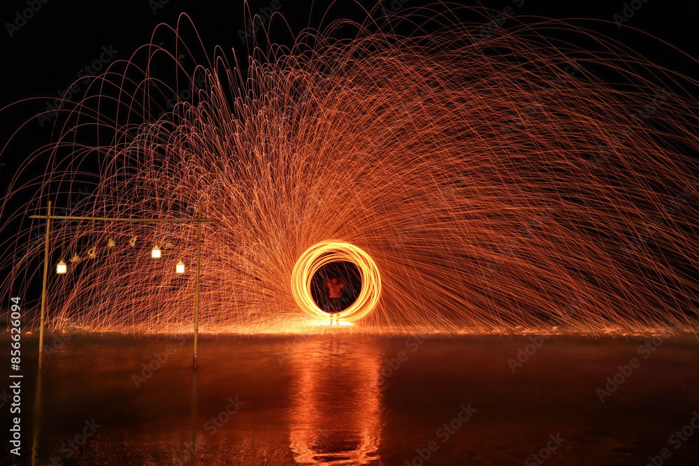 Fire dancer swing fire dancing show on the beach at night. Man wielding ...