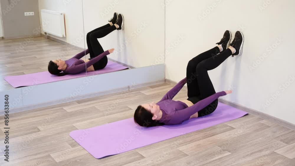 Athletic 30 year woman does abdominal crunches leaning her feet with ...