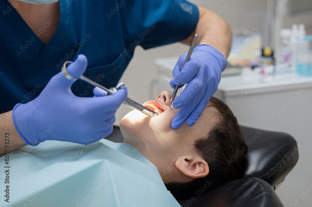 The dentist gives an anesthetic injection into the gum to a boy who is ...