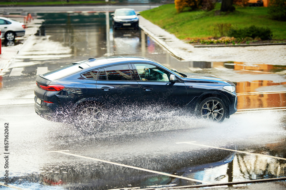 SUV driving through puddle, fast driving on wet road during rain ...