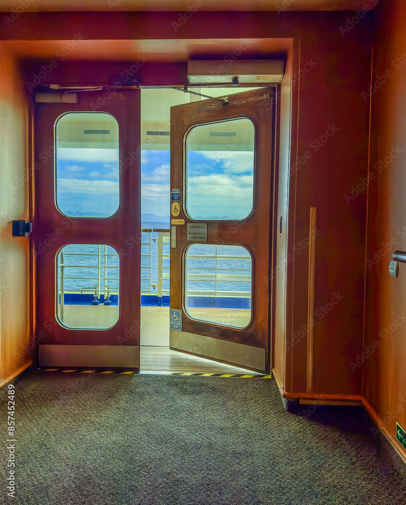 Open door on a cruise ship shows the deck and ocean view beyond ...