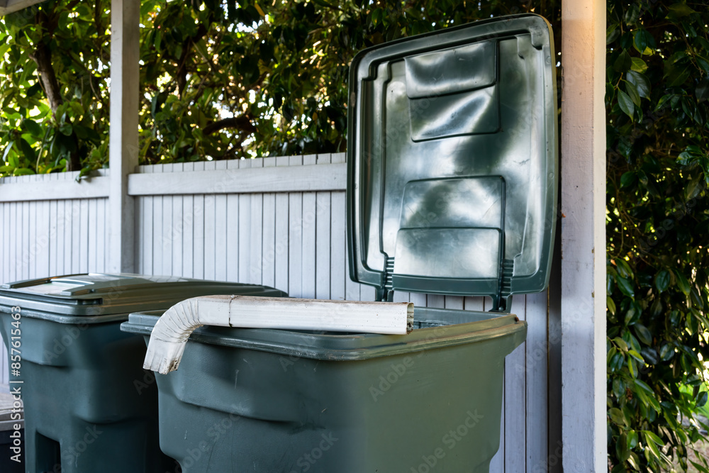 Piece of white metal rainwater downspout balanced on large green yard ...