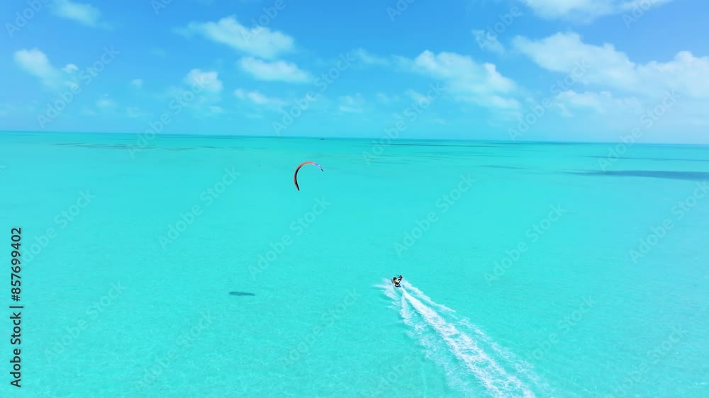 Circling shot shows a kite surfer cruising forward on the stunning blue ...