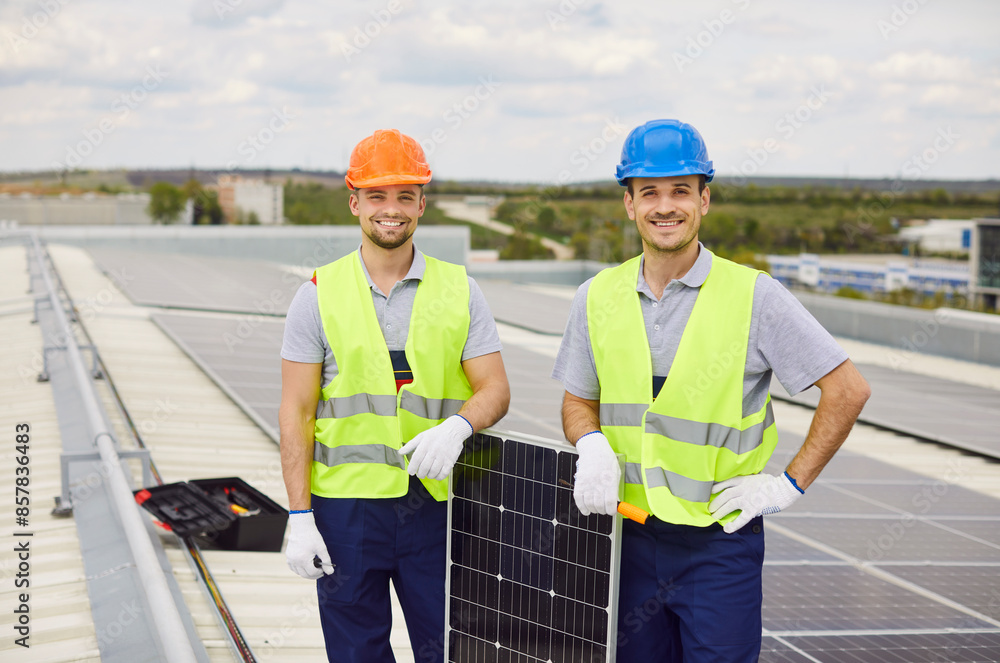 Portrait of happy workers installing solar panels on a roof ...