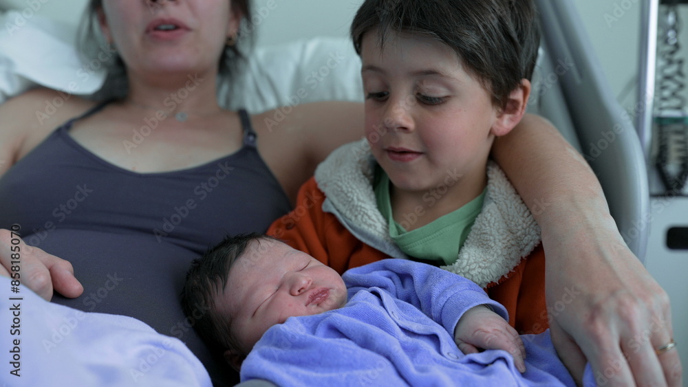 Sibling looks lovingly at newborn baby while sitting beside their ...