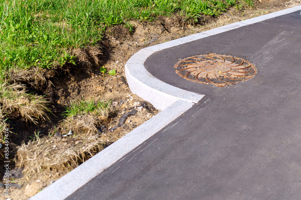 Asphalt sidewalk with a raised curb for a manhole cover, blending ...
