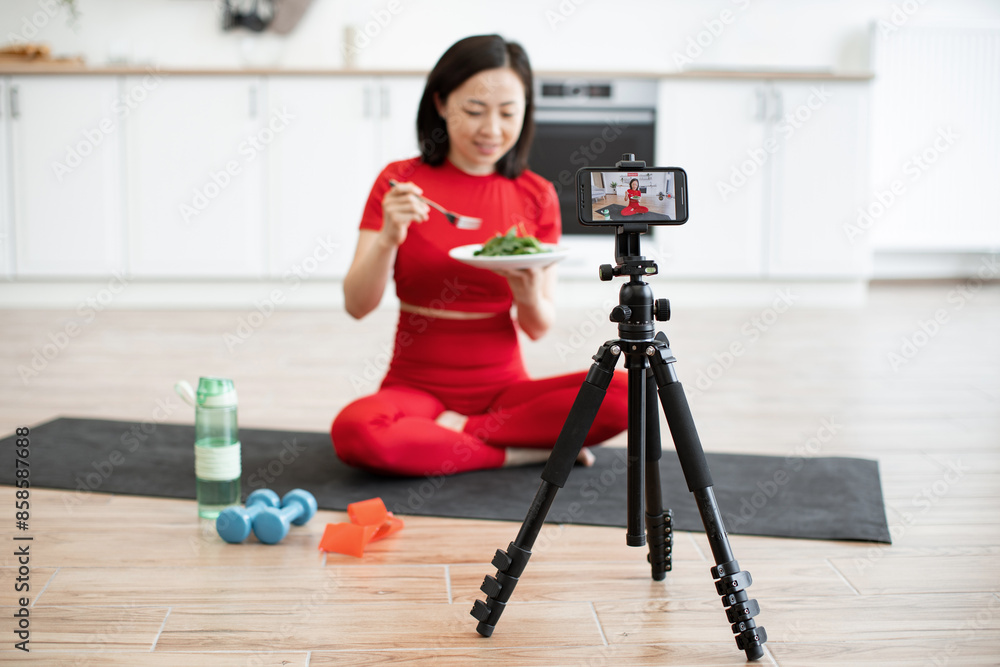 Woman in red workout outfit recording herself eating healthy food ...