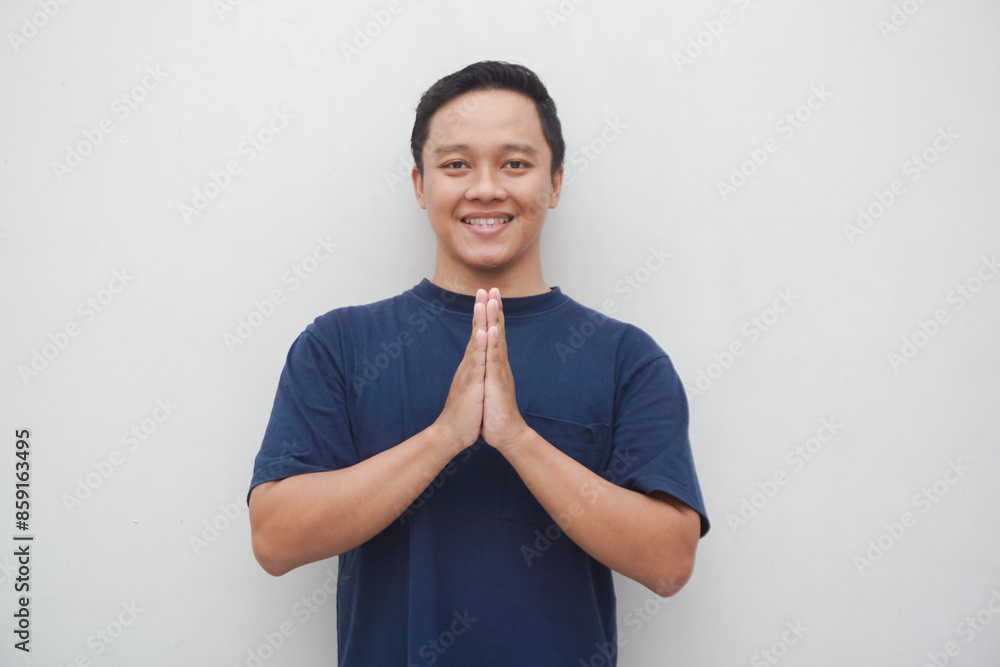 Young Asian man smiling and showing greeting sign isolated on white. A ...
