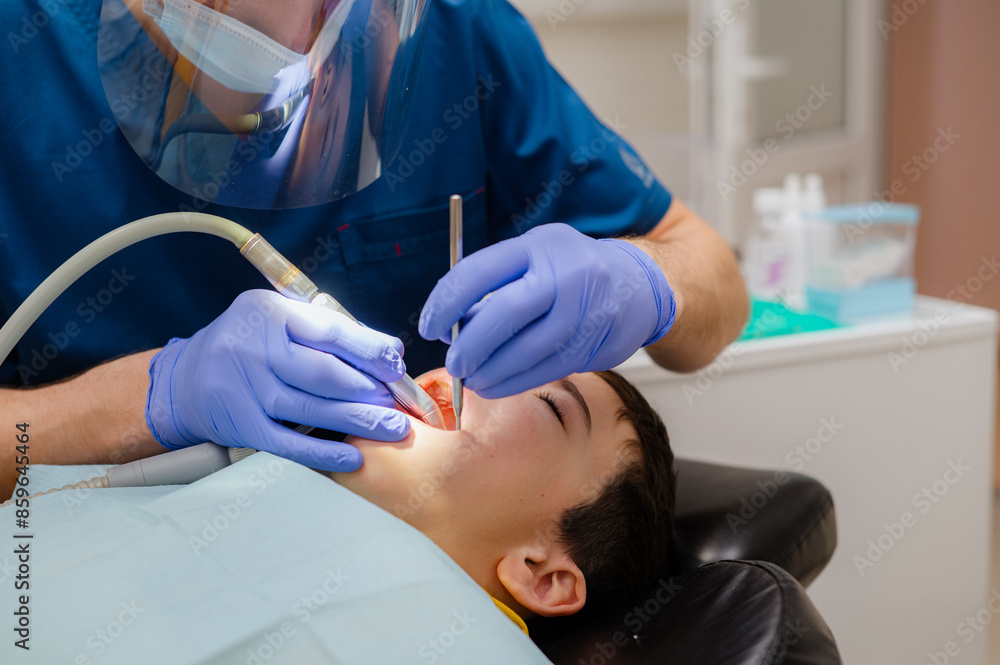 The dentist gives an anesthetic injection into the gum to a boy who is ...