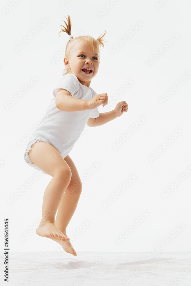 Cute little baby girl, jumping of joy and happiness on white bed ...