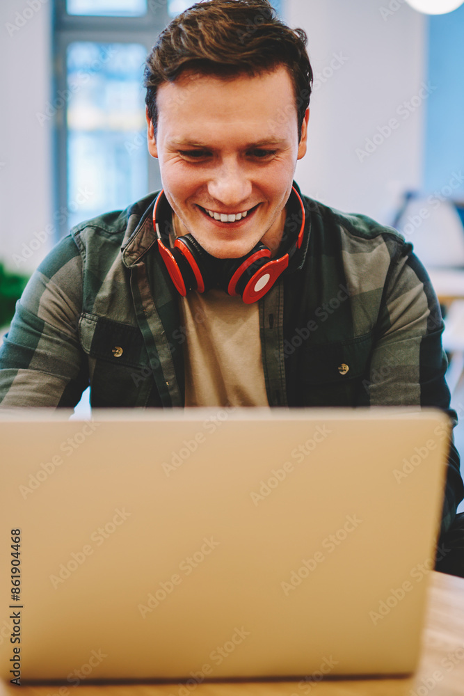 Excited hipster guy enjoying playing online games on laptop computer in ...