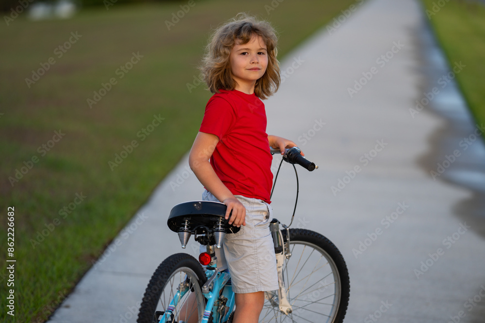 Little kid boy ride a bike in the park. Kid cycling on bicycle. Happy smiling child riding a ...