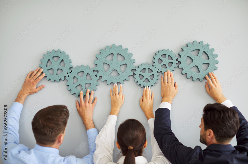 A group of business people standing connecting gears on the wall, close ...