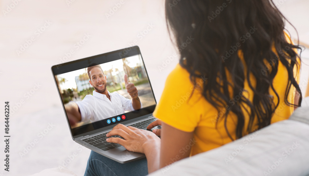 Black woman is seated on a couch, video chatting with a man on her ...