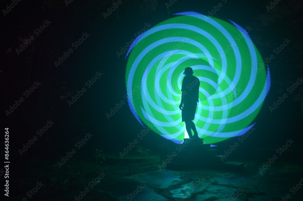 One person standing alone against a Colourful circle light painting as ...
