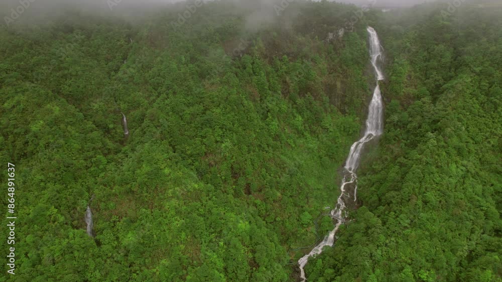 A misty and cloudy aerial perspective captures a multi-tiered waterfall ...