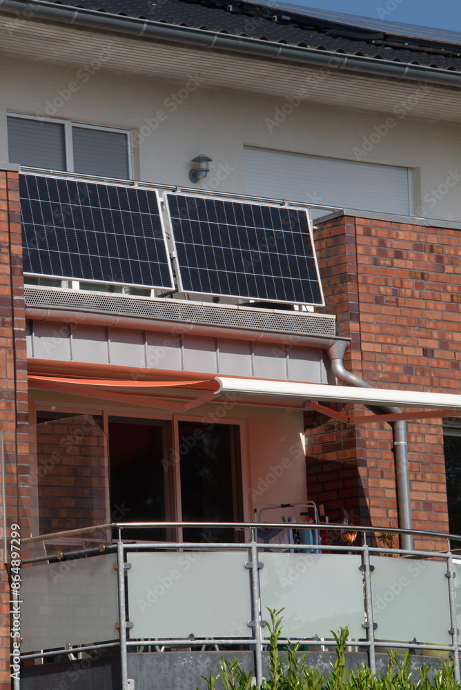 Modern residential building with solar panels on a balcony railing and ...