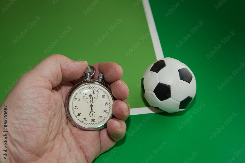 Football ball and mechanical stopwatch in hand and dollars with a ...